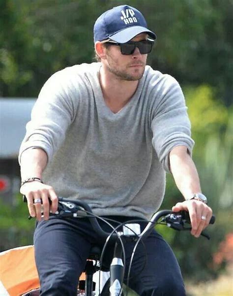 The Man Is Riding His Bike On The Street And Wearing A Hat With No Visor