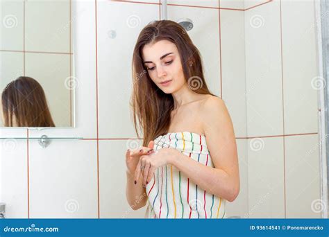 Young Tender Brunette In Towel Stands In The Bathroom And Putting Hand