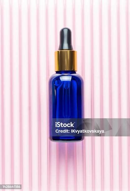 블루 글래스 드로퍼 병에는 뷰티 케어 세럼 히알루 론산 및 비타민이 분홍색 배경에 있습니다 가정용 화장품 및 스파 컨셉 0명에