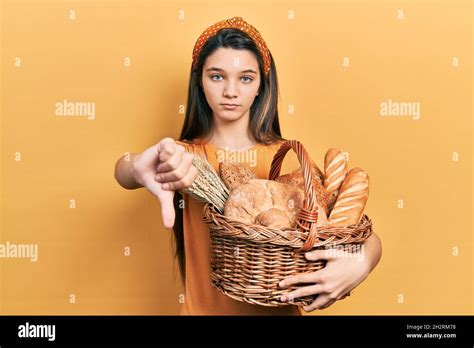 Young Brunette Girl Holding Wicker Basket With Bread With Angry Face
