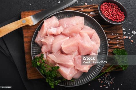 생 닭 가슴살은 어두운 슬레이트 돌 콘크리트 배경에 허브와 향신료가있는 나무 커팅 보드에 조각을 슬라이스하거나 자릅니다 생 닭
