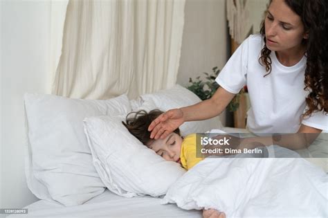 걱정이 많은 어머니는 손으로 아픈 소년의 온도를 확인합니다 독감 이나 보조 병 침대에서 자 고 아픈 아이 2명에 대한 스톡 사진