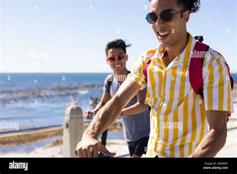 Happy Biracial Gay Male Couple Riding Scooters On Promenade By The Sea Stock Photo Alamy