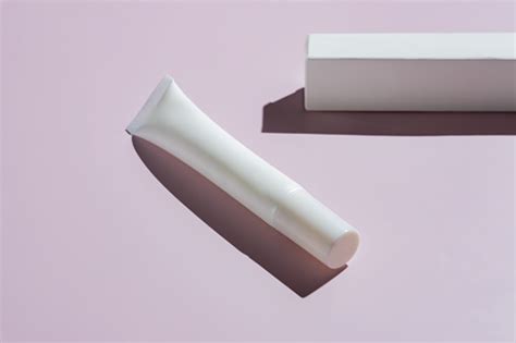 아이 크림 패키지 모형 가혹한 그림자가 있는 분홍색 배경에 브랜드가 없는 플라스틱 튜브와 종이 상자 0명에 대한 스톡 사진 및