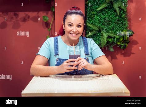 Young Woman Smiling At Camera While Drinking A Fresh Smoothie At A