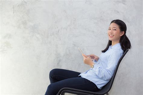 아름 다운 젊은 아시아 여자 태블릿 컴퓨터와 시멘트 배경 프리랜서 여성 호출 전화 통신 개념에 앉아 미소를 감동 디지털 태블릿