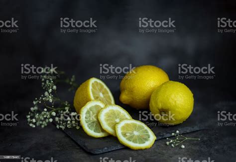 어두운 배경에 흰색 꽃이 있는 테이블에 전체 레몬과 얇게 썬 레몬 조각으로 구성된 우아한 겨울 정물 0명에 대한 스톡 사진 및 기타 이미지 Istock
