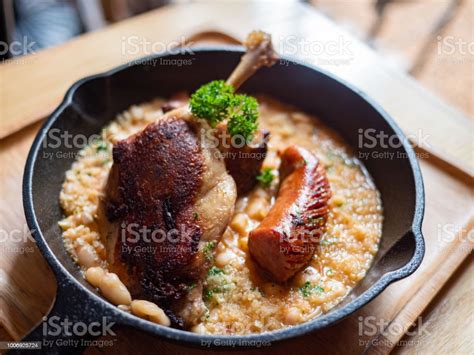 트리오 오리 Confit 삼겹살과 훈제 소시지 검은 무 쇠 냄비에 흰 콩의 침대에서 스튜 오리 물새에 대한 스톡 사진 및 기타