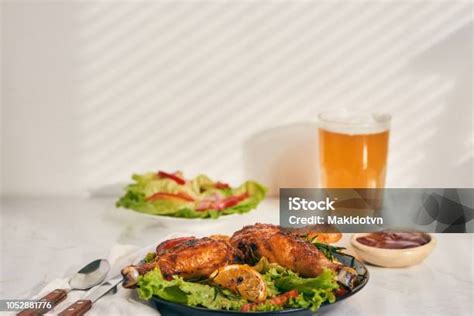 그릇에 토마토 소스와 함께 어두운 접시에 그릴에 구운된 닭 다리 구이 상 추 잎 맥주의 유리 찻잔 가금류에 대한 스톡 사진 및