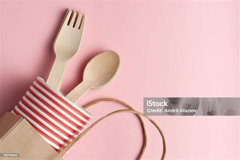 환경 친화적이고 일회용 주방 용품 템플릿 나무 숟가락 포크 종이 컵 분홍색 산호 배경의 종이 패키지로 구성 평평한 평신도 복사