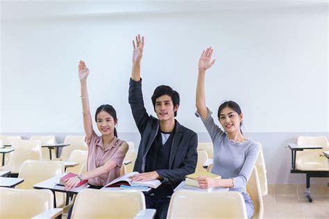 세 사람이 젊은 아시아 남자와 여자 학생 준비 대답을 보여주는 교실에서 손을 높이 교육 투표 프레 젠 테이 션 회 및 세미나의