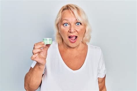 Middle Age Blonde Woman Holding Cosmetic Moisturizer Facial Cream