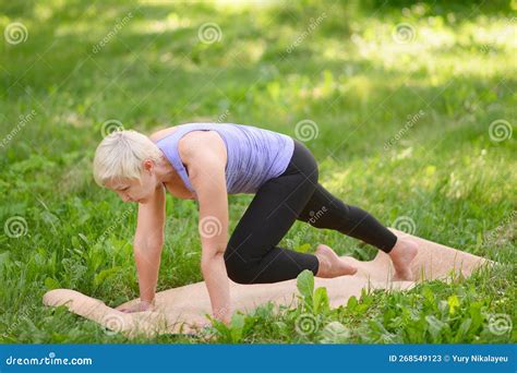 Full Length Portrait Of A Middle Aged Woman Doing Yoga Or Pilates On A
