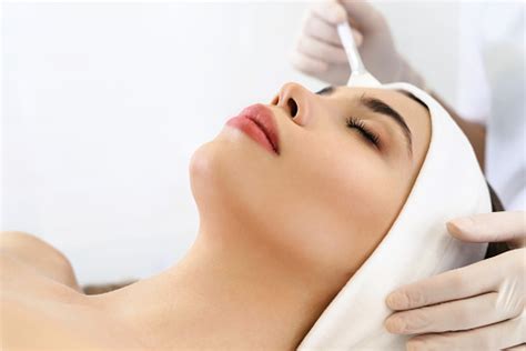 닫힌 눈으로 소파에 누워 흰색 머리 띠 붕대 캡 모델 브러시와 함께 그녀의 얼굴을 만지고 흰색 장갑에서 미용사의 손 머리와 어깨