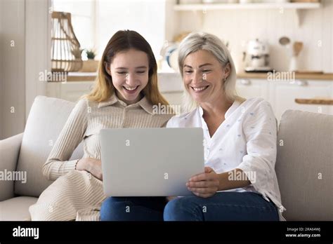 Happy Teen Girl And Cheerful Grandma Having Fun On Home Couch Stock