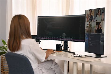 Rear View Of Female Developer Having Video Conference And Working With