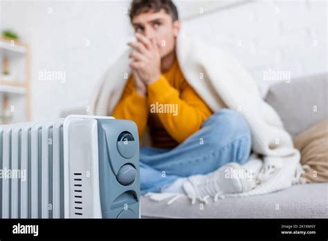 Modern Radiator Heater Near Blurred Man Covered In Blanket Sitting On Sofa Stock Image Stock