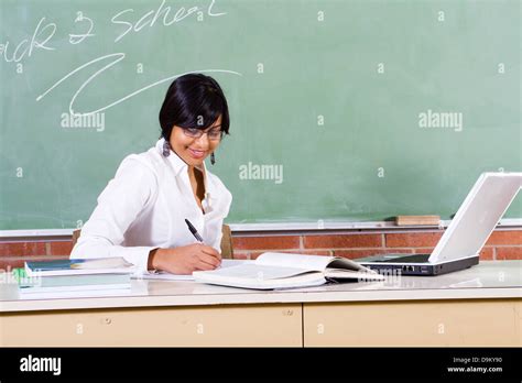Young Female School Teacher Preparing Class Material In Classroom Stock
