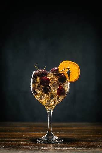 오렌지 조각으로 장식된 나무 테이블에 서 있는 유리에 체리가 있는 노란색 칵테일 술 마실 것에 대한 스톡 사진 및 기타 이미지 술 마실 것 레몬 어두운 색 Istock