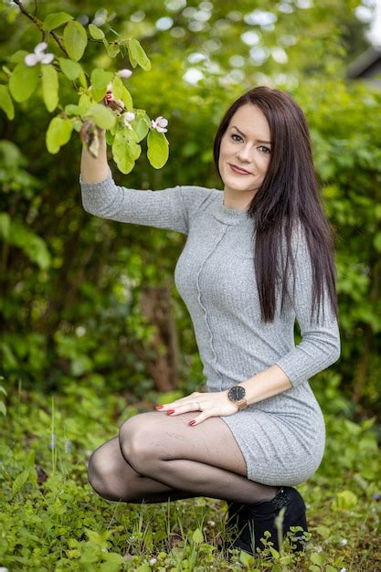 Premium Photo Young Woman In Grey Dress Squats Under An Apple Tree In