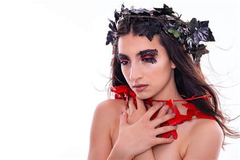 매력적인 젊은 여성 모델의 초상화입니다 소녀는 흰색 배경스튜디오에서 머리에 장식으로 포즈를 취하고 있습니다 장식처럼 검은 색과 빨간색 잎 눈에 환상적인 메이크업 20 29