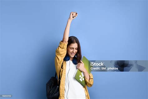 행복한 학생 소녀는 예 중요한 시험을 통과 흥분에 주먹으로 손을 제기 진심으로 미소 책을 들고 노란색 셔츠 흰색 티셔츠 검은