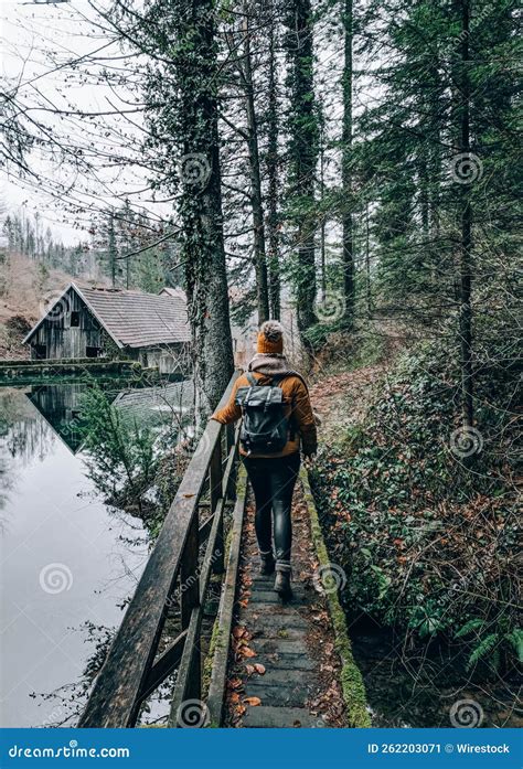 Vertical Shot Of A Female Backpacker Walking On An Old Wooden Bridge By