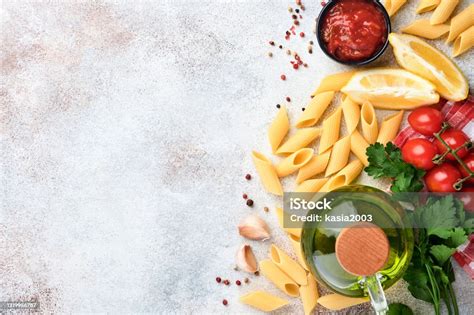 파스타 배경 파스타 리가티 토마토 케첩 소스 올리브 오일 향신료 파슬리 신선한 토마토가 밝은 회색 슬레이트 테이블에 놓입니다