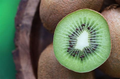 나무 과일 그릇에 담긴 키위 과일 더미의 전체 프레임 이미지 반으로 자른 중국 구스베리는 흐릿한 갈색 피부와 밝은 녹색 과육에 검은 씨앗 고리 얼룩덜룩한 녹색 배경 높은 0