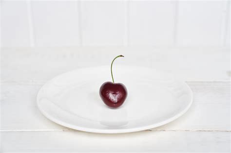 흰색 배경에 익은 신선한 육즙 베리 흰 접시에 하트 모양의 체리 하나 과일 배경입니다 발렌타인 데이 복사할 공간이 있습니다