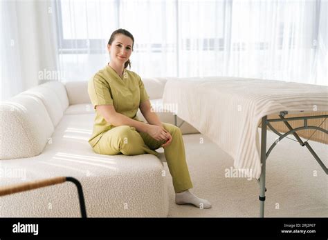 Front View Of Serious Female Pediatric Masseuse In Uniform Sitting