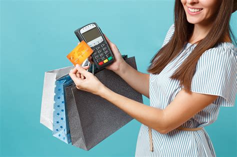 세로 여자 드레스 모자 쇼핑 후 구매와 패키지 가방을 들고 무선 현대 은행 결제 처리 하 고 신용 카드 결제를 취득 터미널 블루 파스텔 배경에 고립 가방에 대한 스톡 사진