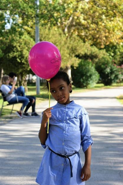 Premium Photo Girl Holding Balloon On Footpath At Park