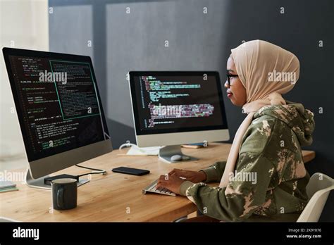 Side View Of Young Muslim Female Programmer Looking Through Coded