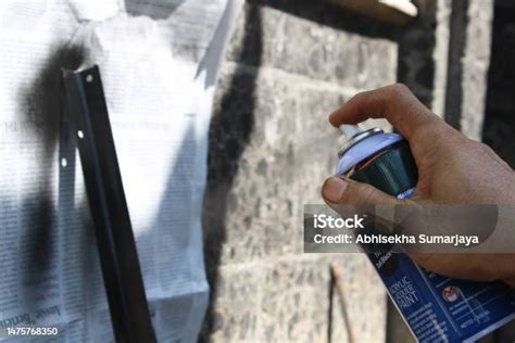 선반을 만들기 위해 스프레이 페인트 또는 에어로졸 페인트로 강철 앵글 또는 앵글 아이언을 검은색으로 칠하는 작업자 각도에 대한