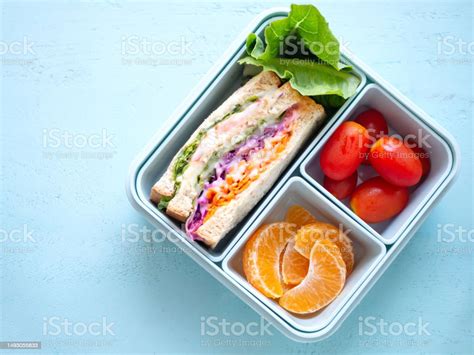 파란 나무 배경에 샌드위치와 오렌지 토마토 야채가 있는 수제 건강한 파란색 도시락 복사 공간이 있는 평면도입니다 0명에 대한