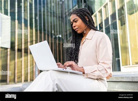A Focused Professional Woman Works On Her Laptop Outside Modern