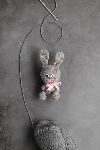 부활절 공예 Diy 수제 크로 셰 뜨개질 토끼 장난감 양모 원사의 공 어두운 회색 배경에 뜨개질 바늘 오버헤드 뷰 텍스트 공간