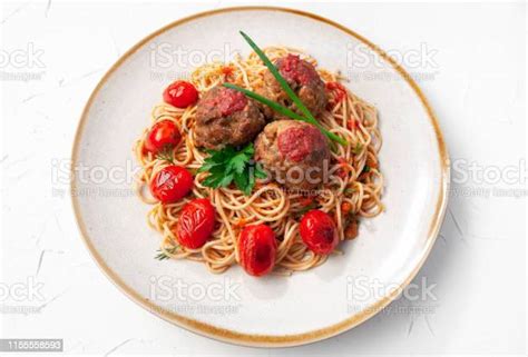 미트볼과 토마토 소스가 들어간 파스타 채소와 구운 체리 토마토로 장식 되어 있습니다 원래 접시에 위에서 보기 흰색 바탕에 절연 된 하드 라이트 고기에 대한 스톡 사진 및