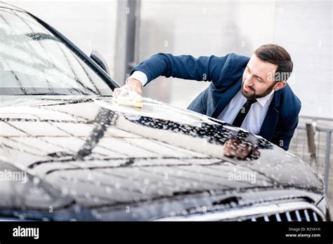Elegant Businessman Dressed In The Suit Washing His Car With Yellow