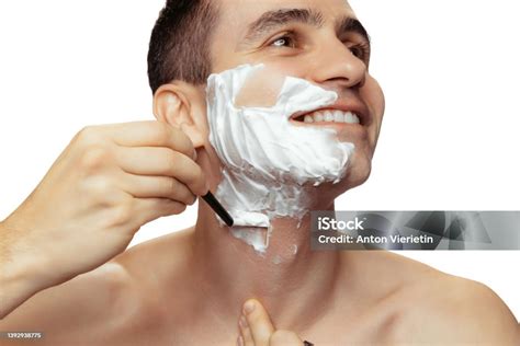 하얀 스튜디오 배경에 고립 된 크림과 면도기로 면도하는 얼굴을 가진 젊은 웃는 남자의 초상화 매끄러운 피부 35 39세에 대한