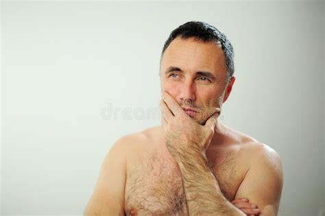 Unshaven Man Touches His Beard With His Hand And Looks Away As If He Is
