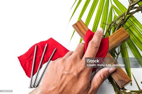 손톱과 야자수 잎이 달린 빨간 천으로 감싼 예수 나무 십자가를 들고 있는 누군가 가톨릭 기독교 성 금요일 의식 빈 복사 텍스트 공간이 있는 흰색 배경에 격리되어 있습니다