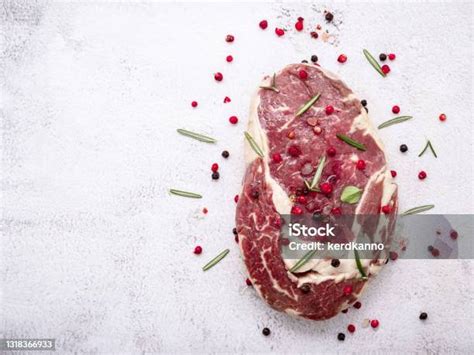 원시 리브 아이 스테이크는 흰색 콘크리트 배경에 설정 로즈마리와 향신료를 곁들인 신선한 생 소고기 스테이크의 플랫 레이가 화이트