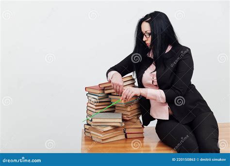 Beautiful Female Teacher In Class At A Table With Stacks Of Educational