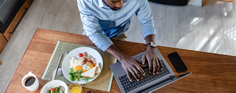 한 남자가 아침 식사 접시 커피 주스를 옆에 두고 식탁에서 노트북으로 작업을 하고 있습니다 이 이미지는 위에서 내려다보는 시점에서 촬영한 것으로 건강한 식사와 작업 환경을