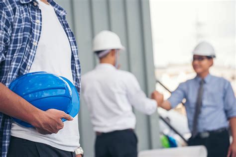 계약자 건설 엔지니어 회의는 건설 사무실 현장의 건축가 테이블에서 함께 이야기합니다 사업가 엔지니어 매니저가 감독과 논의 팀 빌더와 계획 청사진 노트북을보십시오 건물 외관에