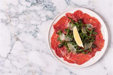 Premium Photo Marbled Beef Carpaccio With Arugula Capers Lemon And
