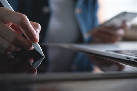 디지털 태블릿 Pc에서 작동하는 스타일러스 펜으로 비즈니스 여성 손을 클로즈업 가정의 사무실 테이블에 모바일 포브와 노트북 컴퓨터를 사용하여 온라인 수업을 공부하는 학생