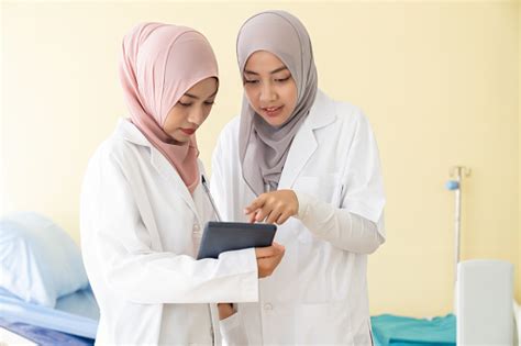 히잡의 무슬림 의사는 태블릿을 사용하여 병원에서 진단 환자를 위해 아랍 의료 팀과 상담 증상을 이야기합니다 2명에 대한 스톡 사진 및 기타 이미지 Istock